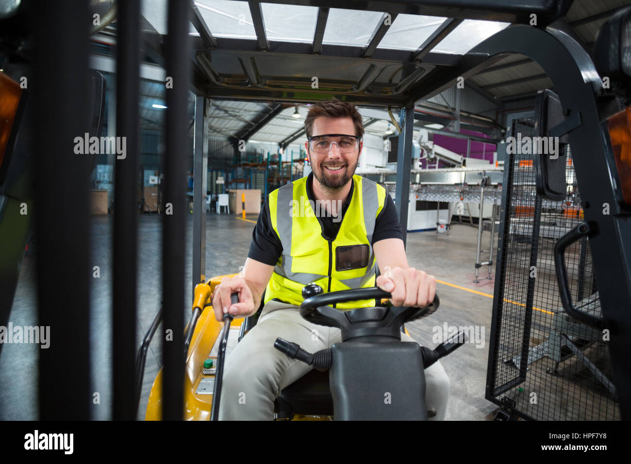 Portrait of smiling factory worker driving forklift in factory Stock ...