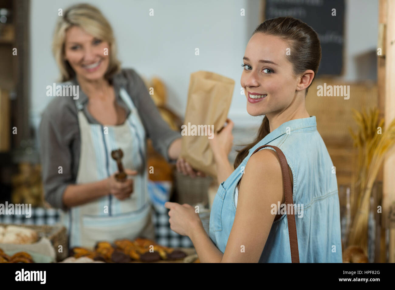 Female customer receiving a parcel from bakery staff at counter in bake ...