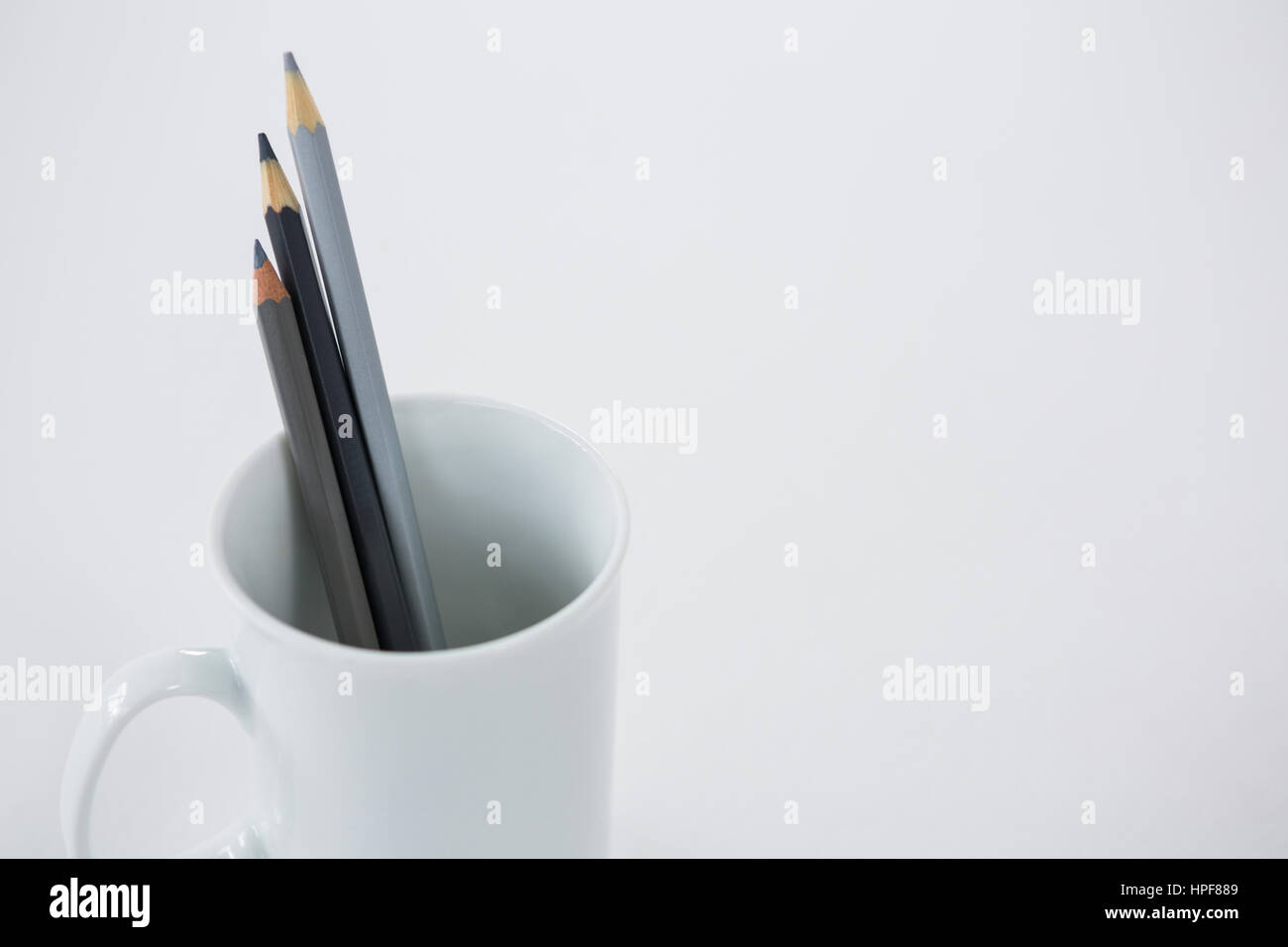 Colored pencils kept in mug on white background Stock Photo - Alamy