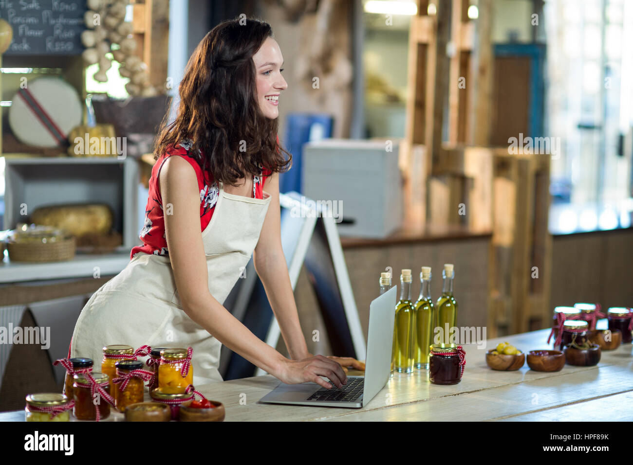 Female shop assistant using laptop at the counter in grocery shop Stock ...