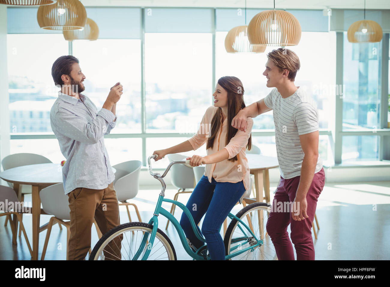 Executives with bicycle having fun in office Stock Photo - Alamy