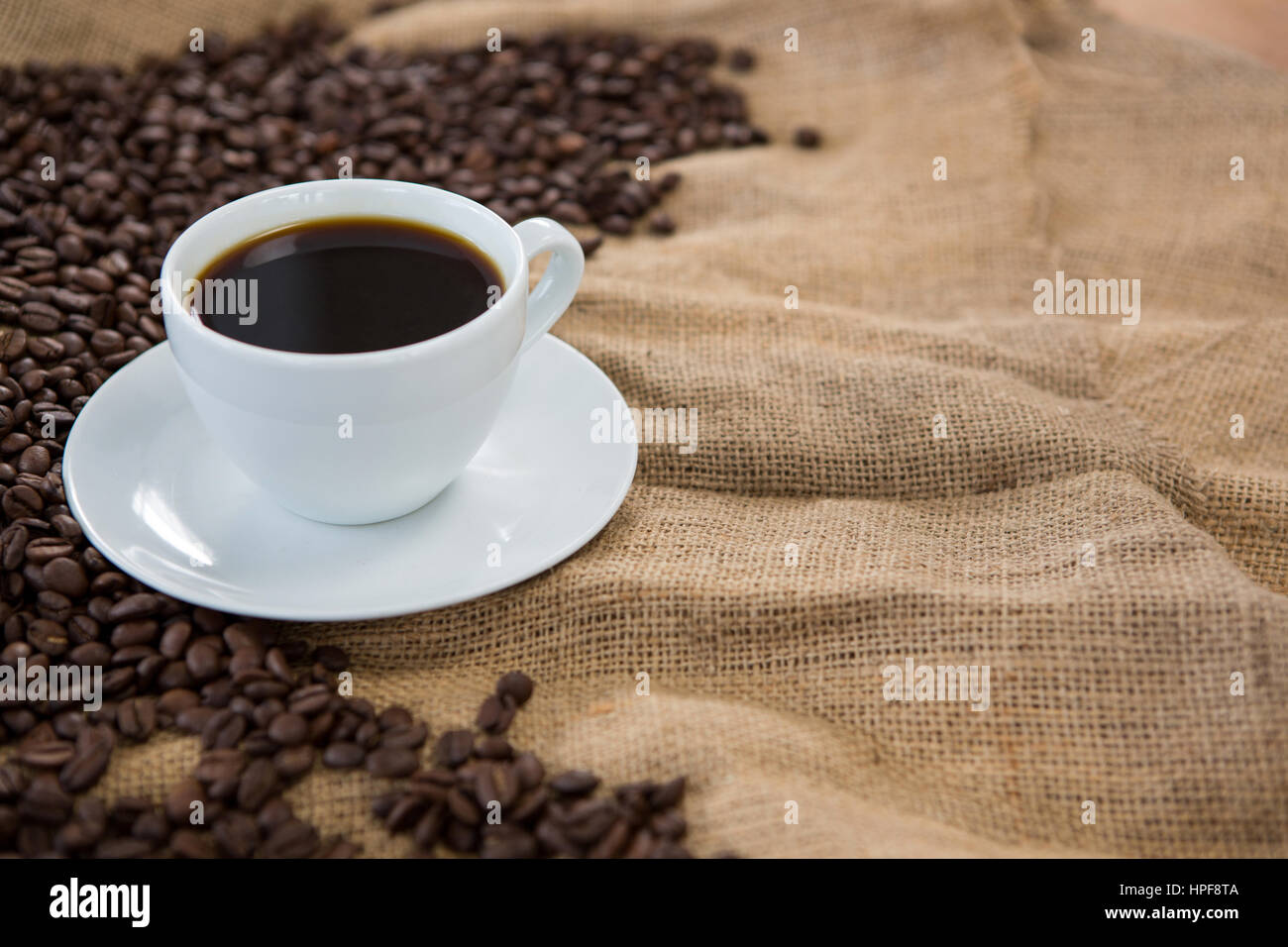 Coffee cup with coffee beans on sack textile Stock Photo - Alamy