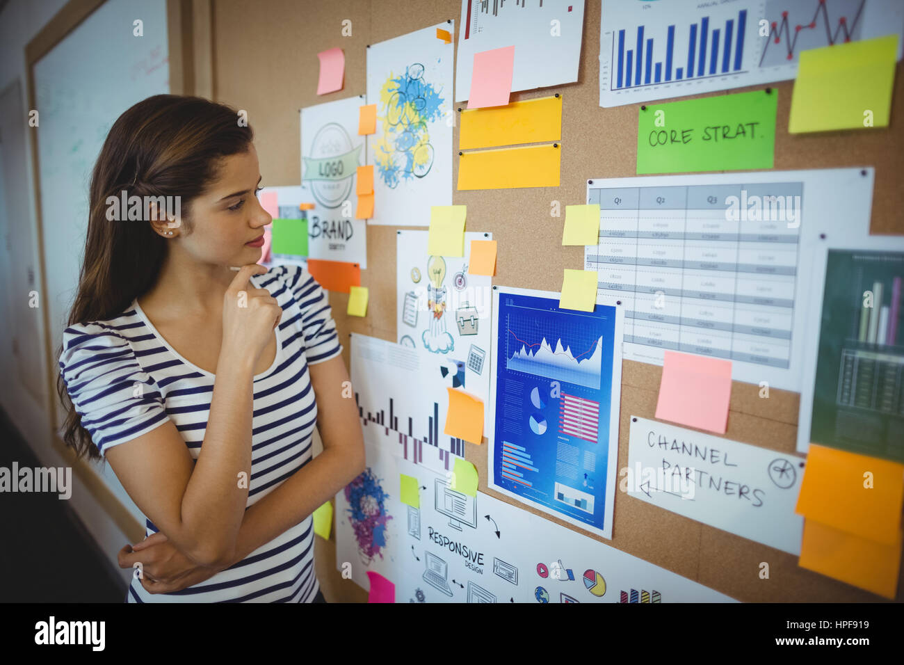 Female executive looking at bulletin board in office Stock Photo - Alamy