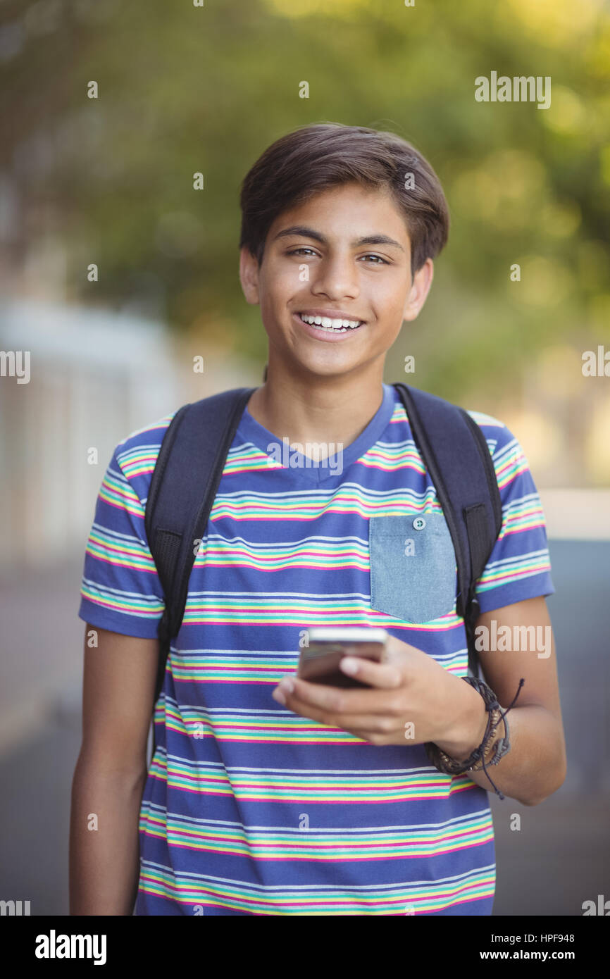 Portrait of schoolboy using mobile phone in campus at school Stock ...