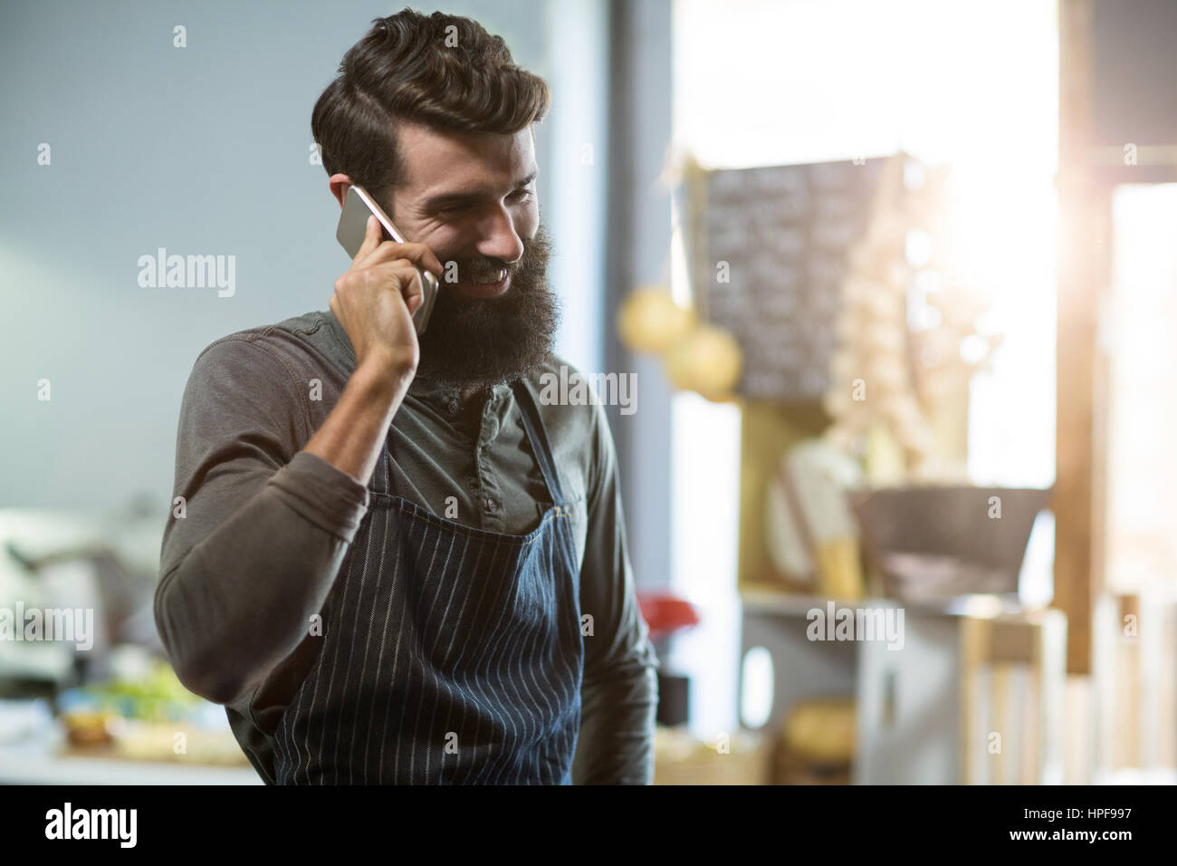 Salesman talking on mobile phone at counter in grocery shop Stock Photo ...