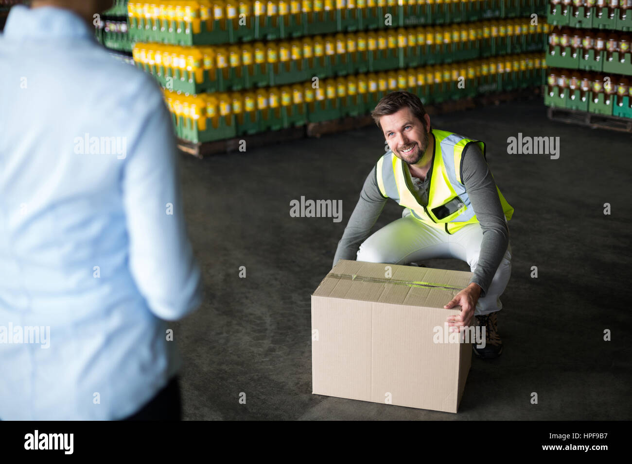 Smiling factory worker picking up cardboard boxes in factory Stock ...