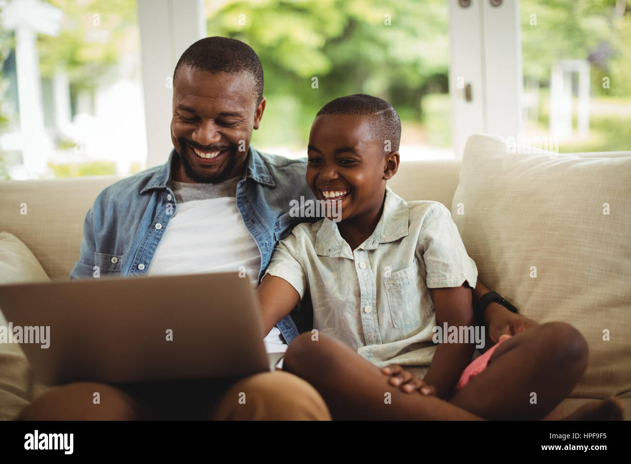 Father and son using laptop in living room at home Stock Photo - Alamy