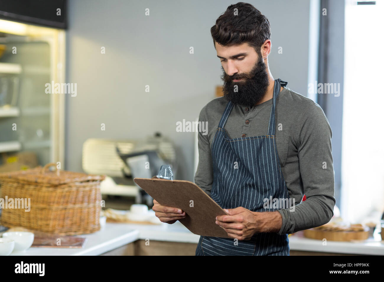Salesman holding clipboard at counter in grocery shop Stock Photo - Alamy