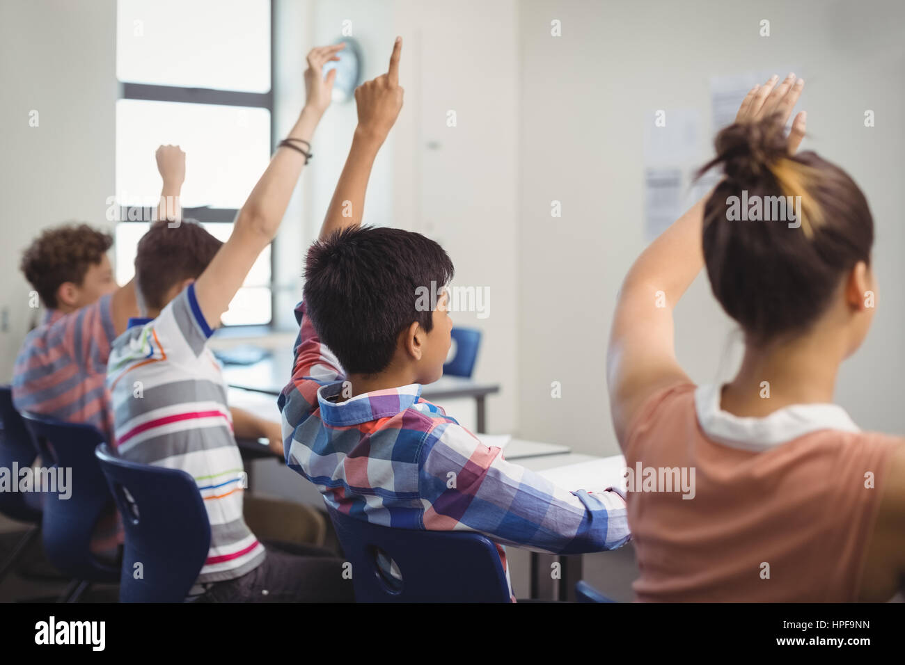 Student raising hand in classroom at school Stock Photo - Alamy