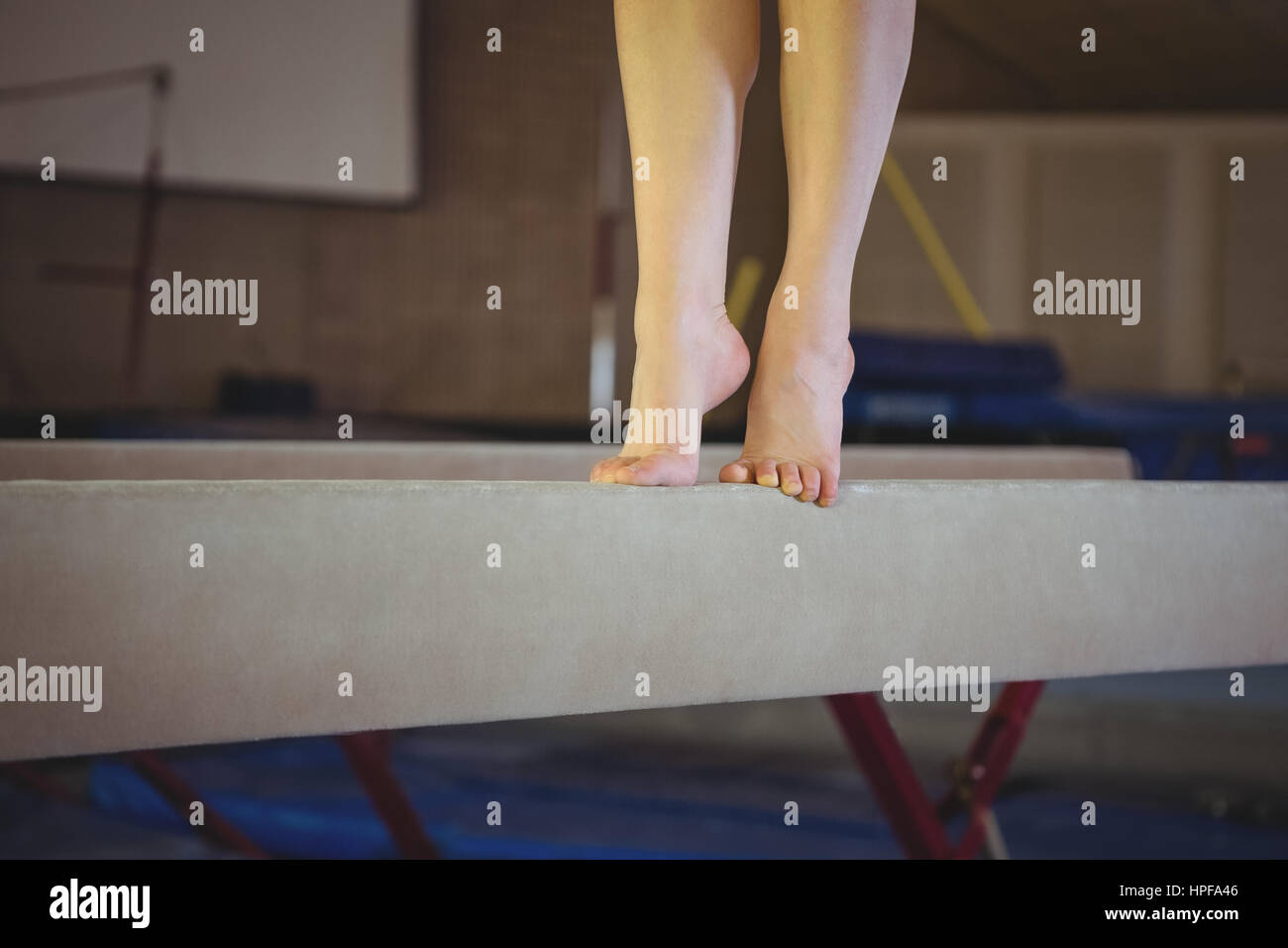 Low-section of female gymnast practicing gymnastics on the balance beam ...