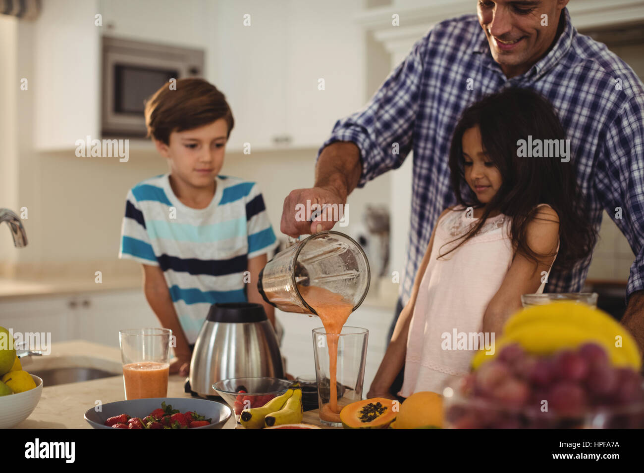 Smiling family preparing smoothie in hi-res stock photography and ...
