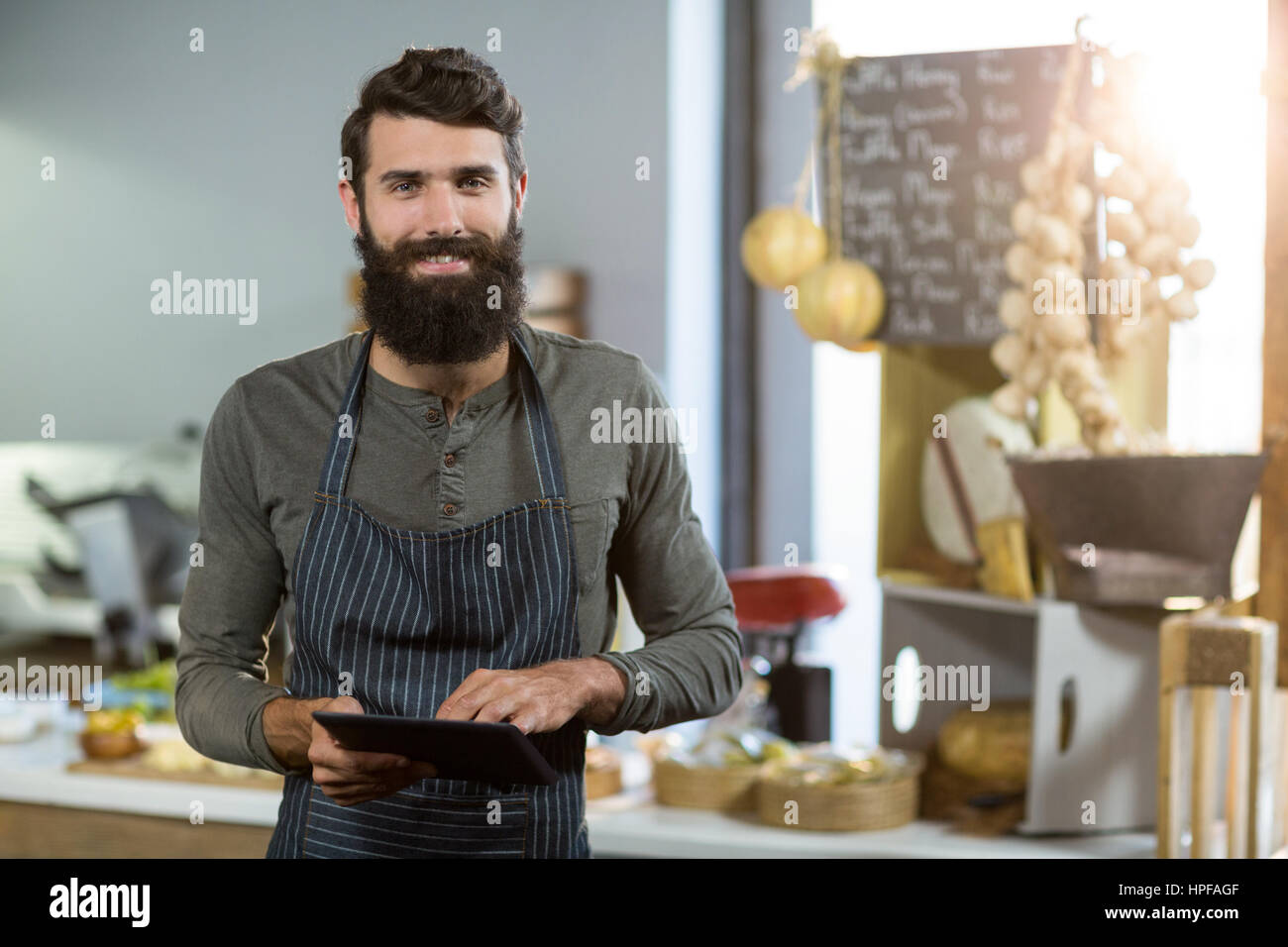 Portrait of salesman using digital tablet at counter in grocery shop ...