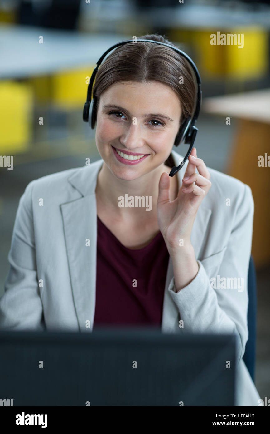 Portrait of smiling business executives talking on headset in office ...