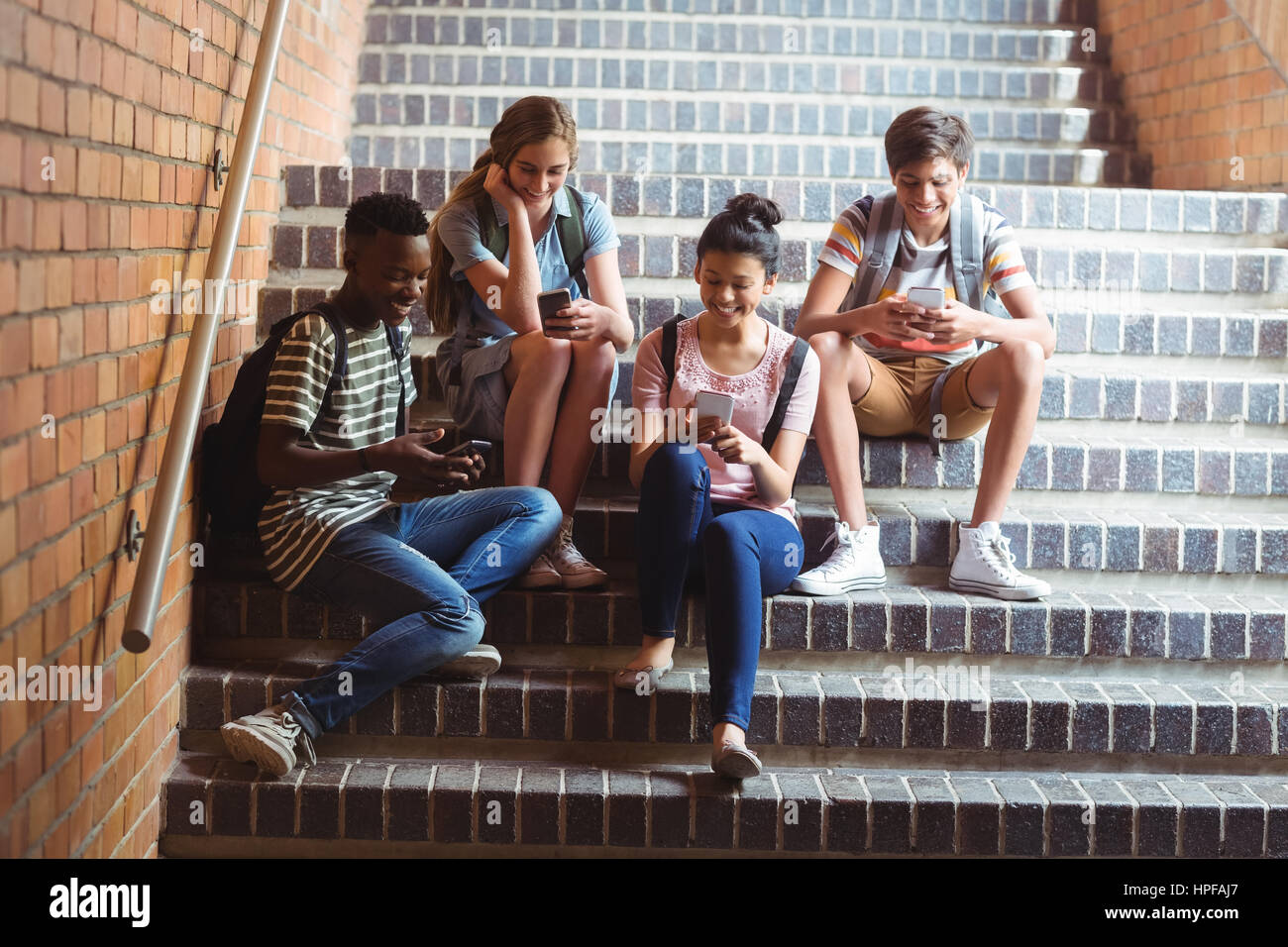 Classmates sitting on staircase and using mobile phone in school Stock ...