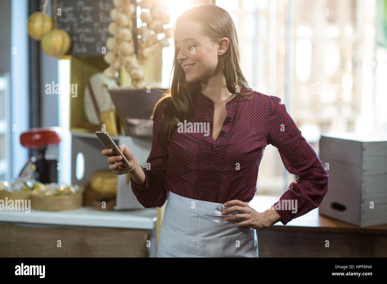 Smiling female staff using mobile phone at counter in bake shop Stock ...