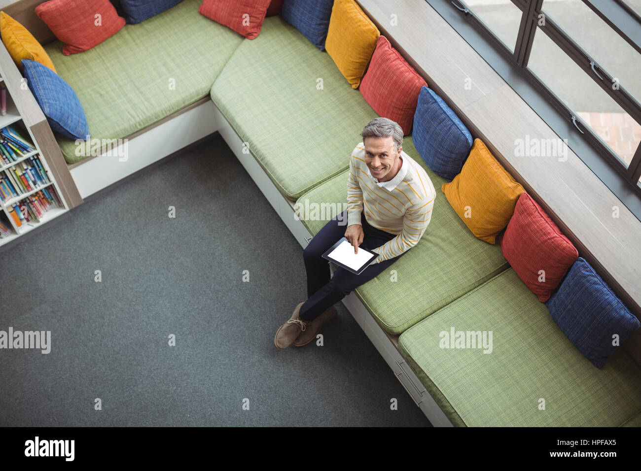 Overhead view of school teacher using digital tablet in library at ...