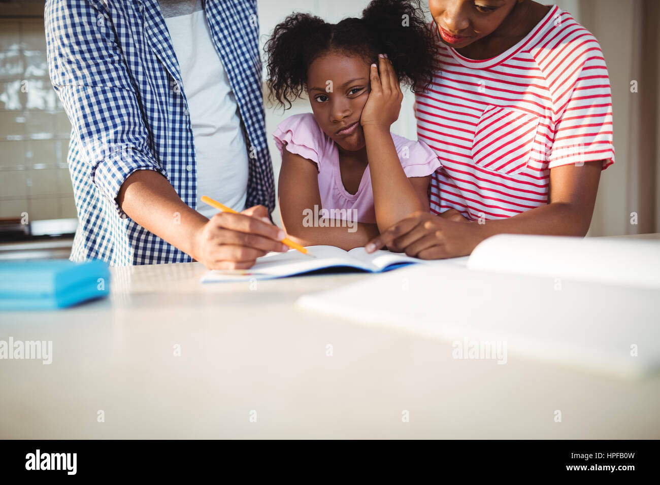 Parents assisting daughter with homework at home Stock Photo - Alamy