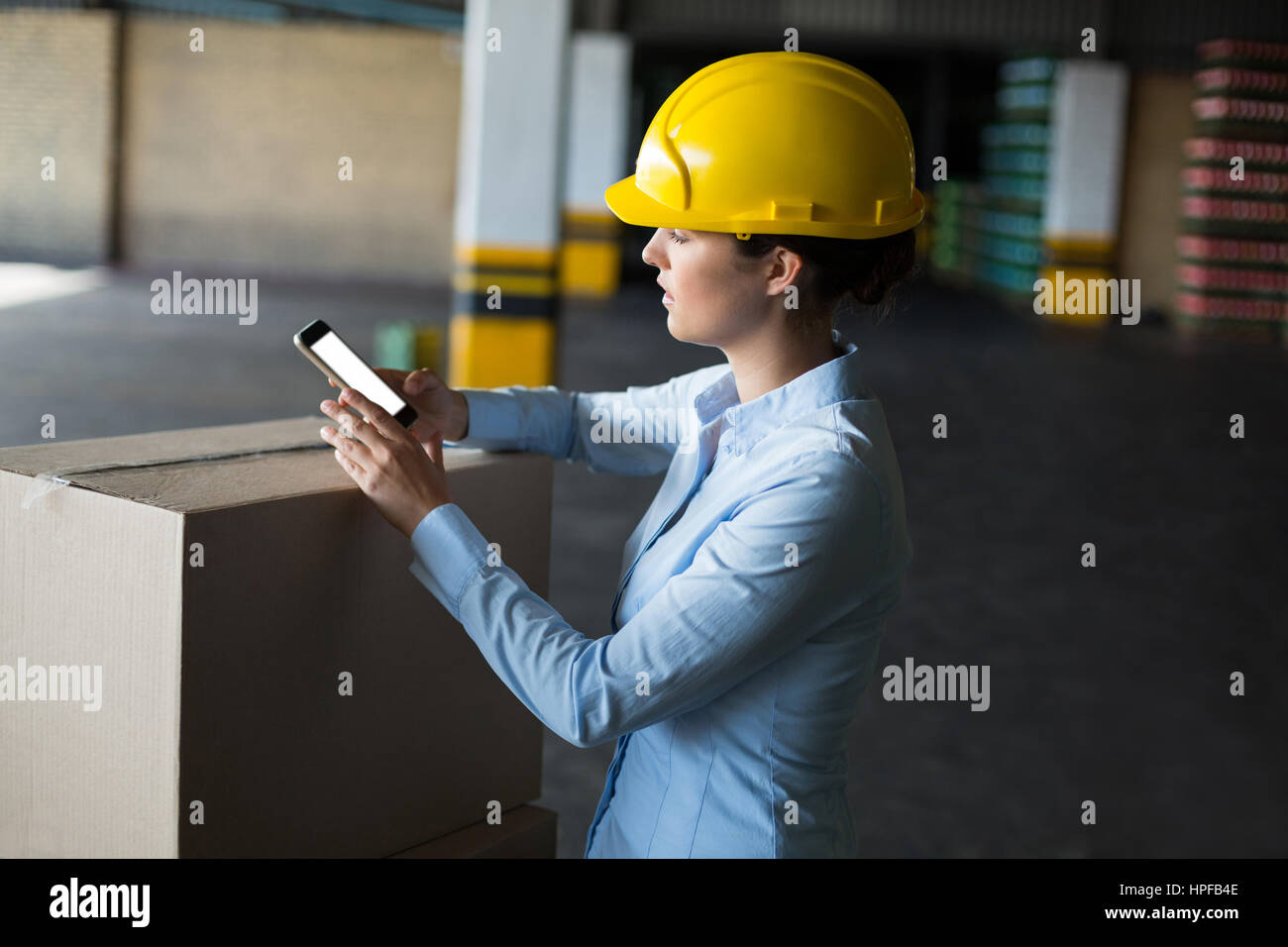 Female factory worker using mobile phone in factory Stock Photo - Alamy