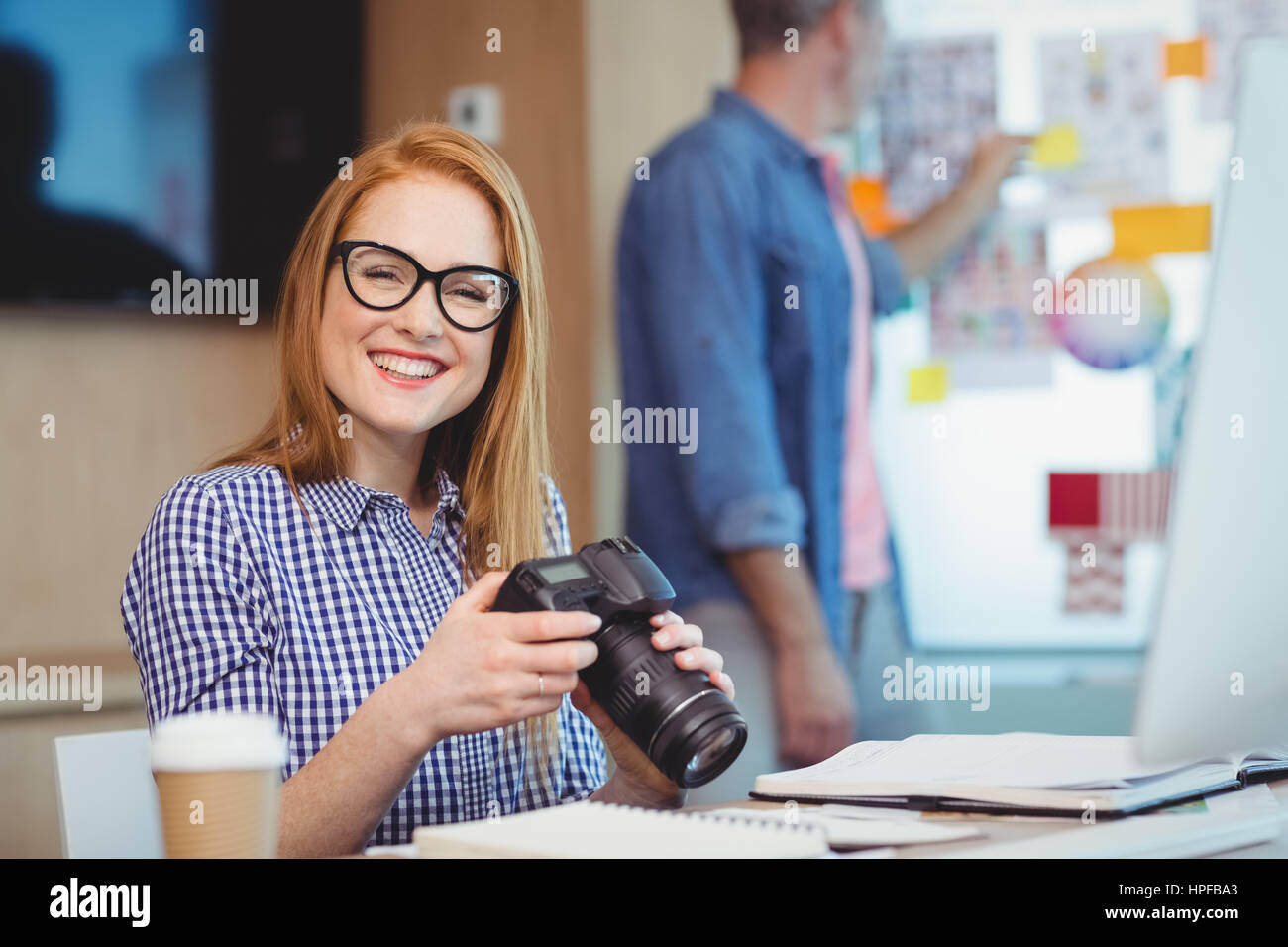 Female graphic designer holding digital camera in office Stock Photo ...