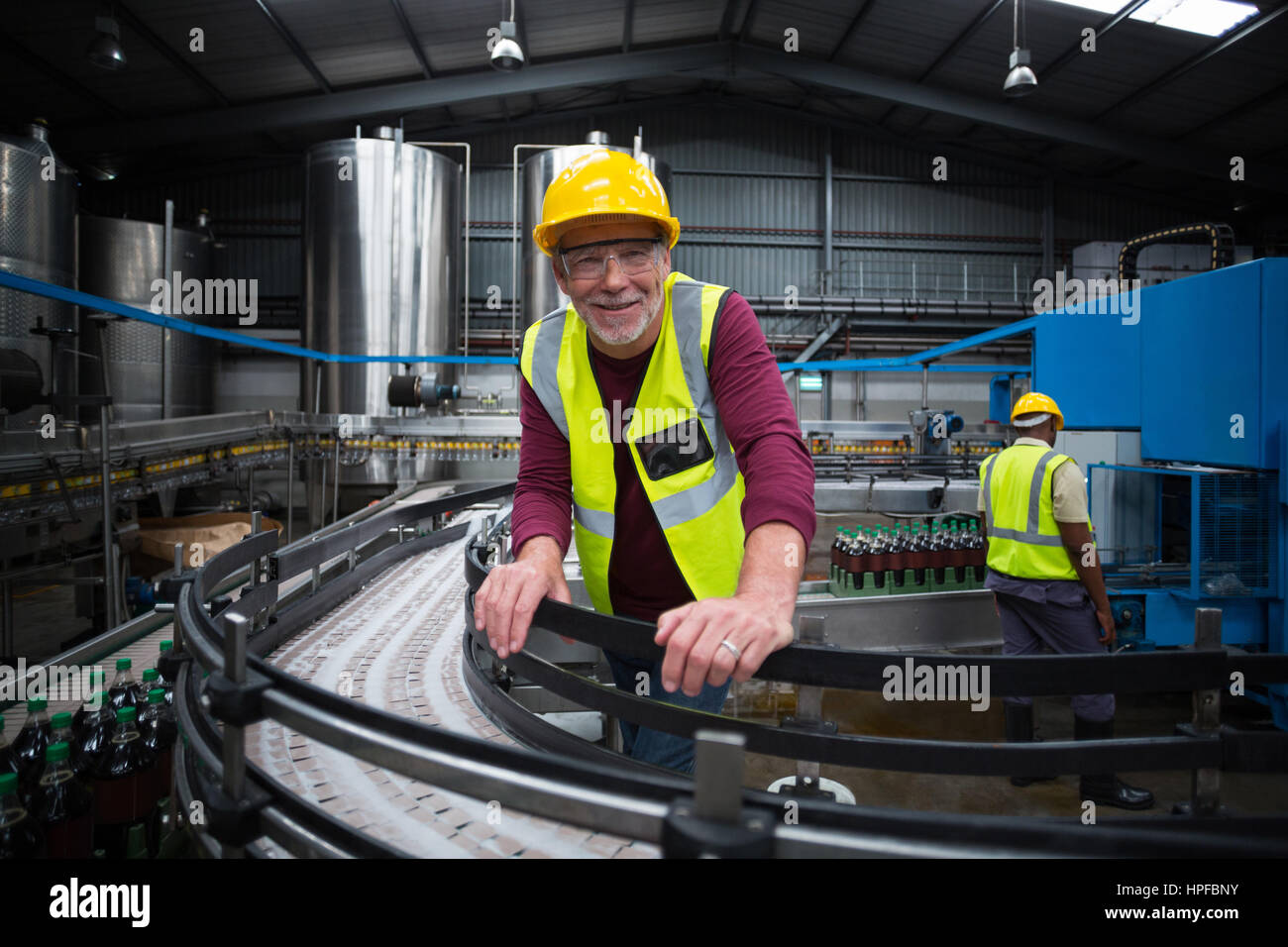 Portrait of smiling factory worker leaning on production line Stock ...