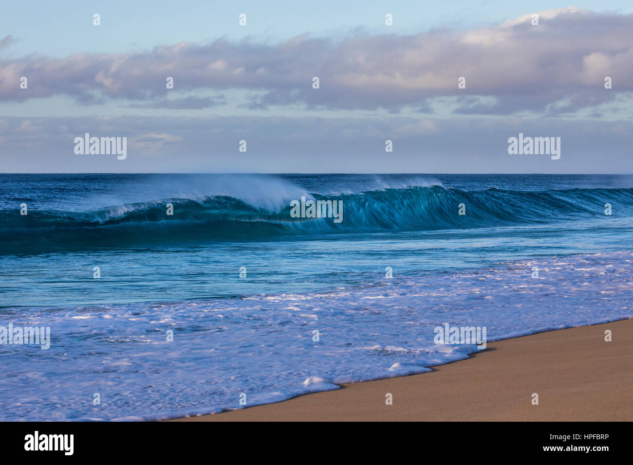 A wave breaking in the late evening along the beach on the North Shore ...
