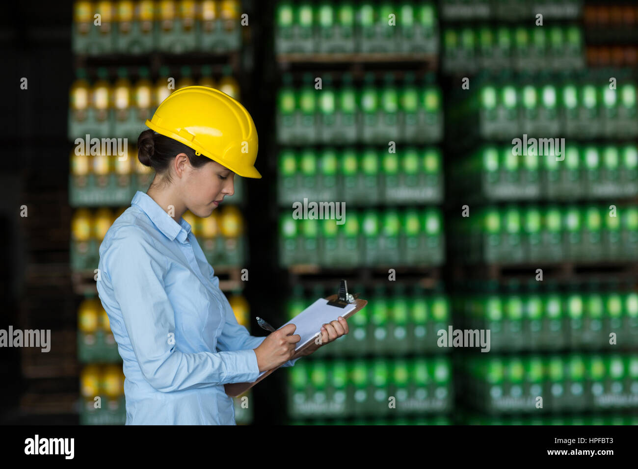 Attentive female factory worker writing on clipboard in factory Stock ...