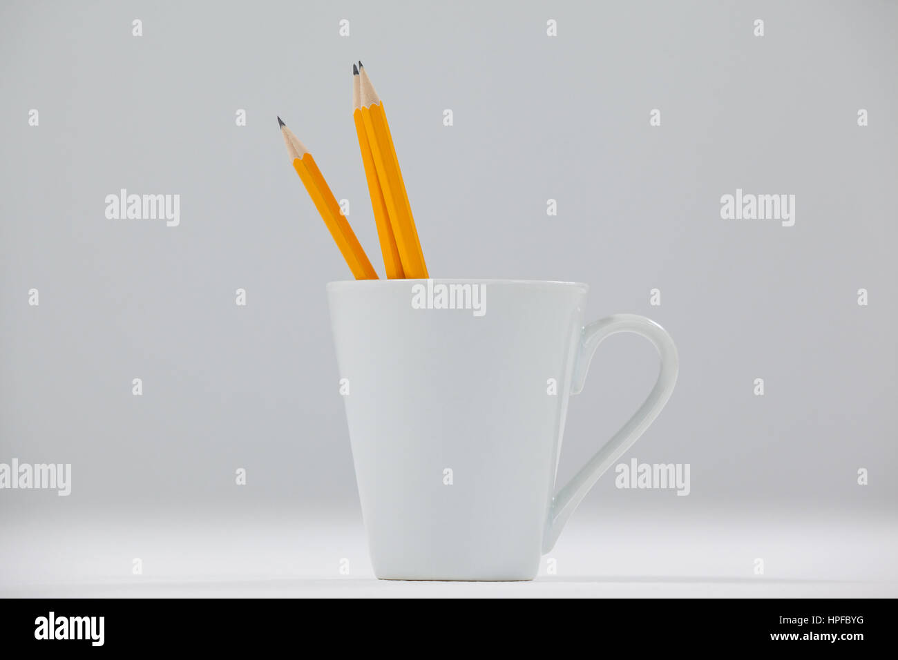 Three pencils kept in cup on white background Stock Photo - Alamy