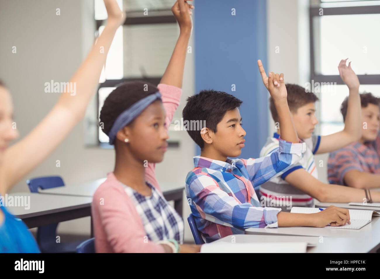 Student raising hand in classroom at school Stock Photo - Alamy