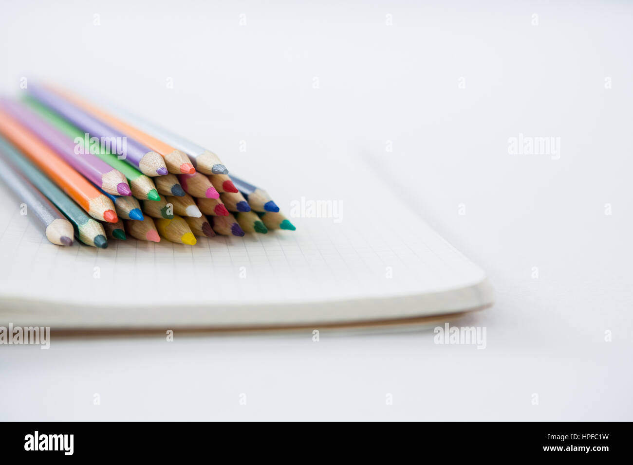 Colored pencils kept on the book on white background Stock Photo - Alamy