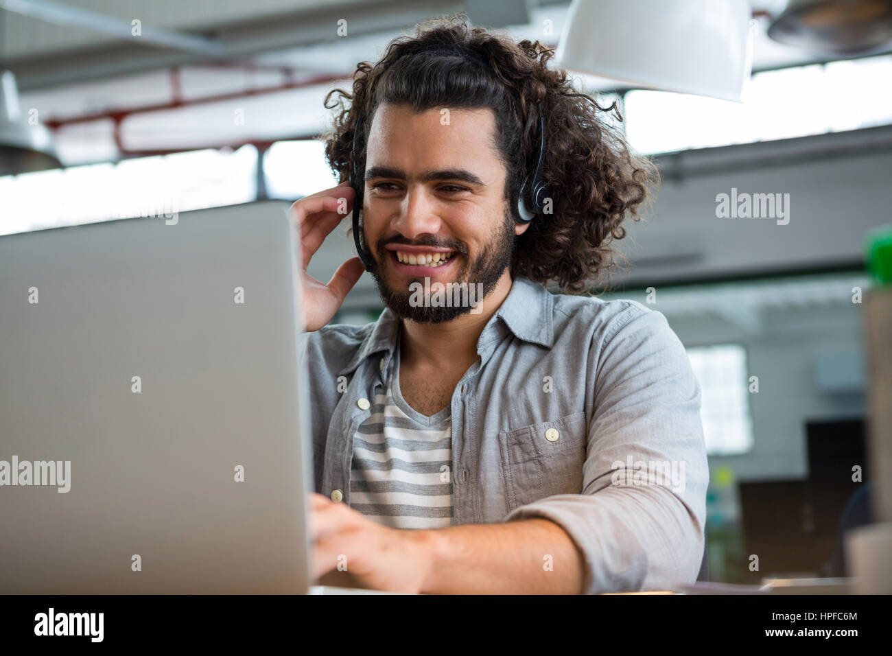 Smiling executive using laptop in creative office Stock Photo - Alamy