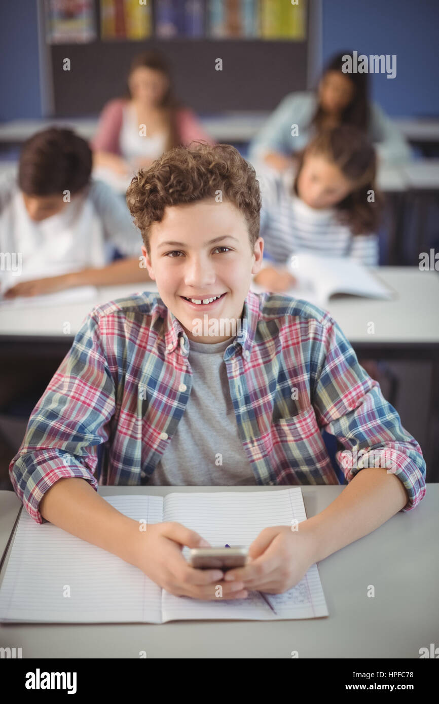 Student holding mobile phone in classroom at school Stock Photo - Alamy