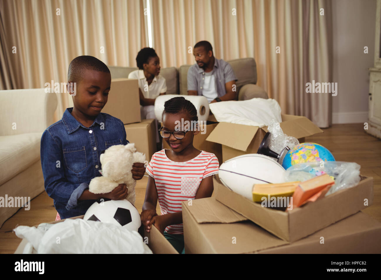 Parents and kids unboxing cardboard boxes in living room at home Stock ...