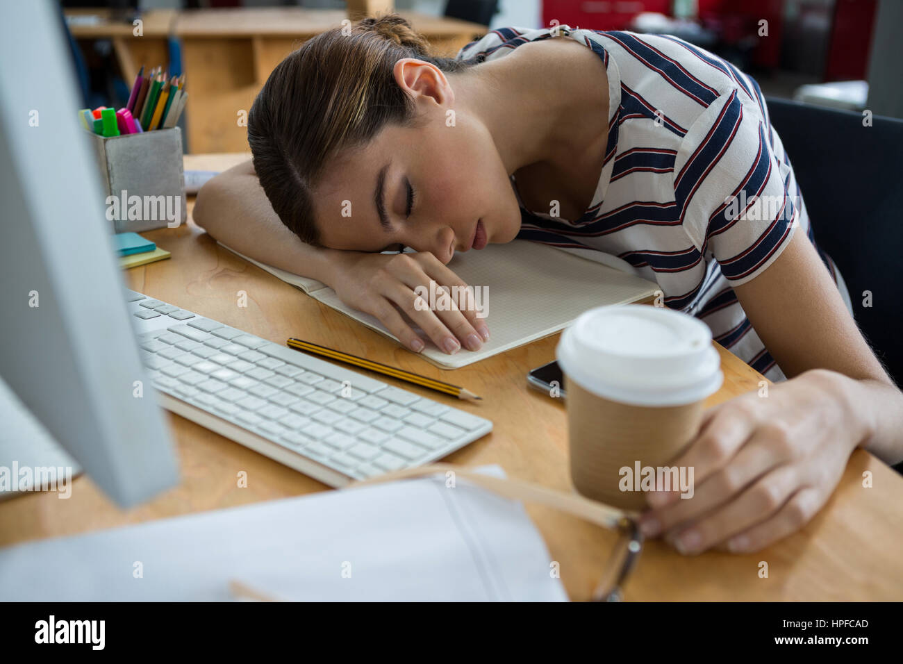 Overworked graphic designer sleeping on his desk in the creative office ...