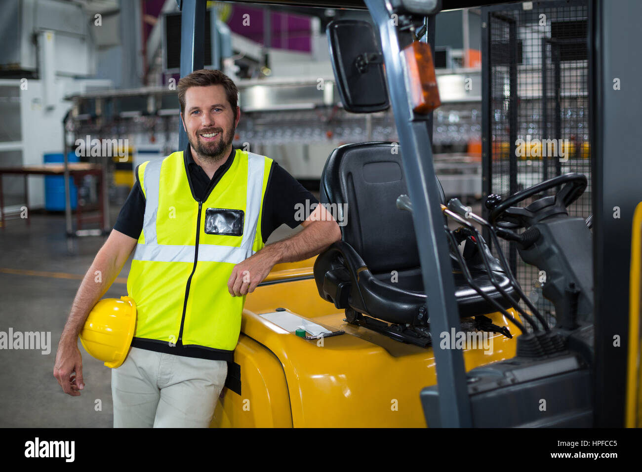 Portrait of smiling factory worker leaning on forklift in factory Stock ...