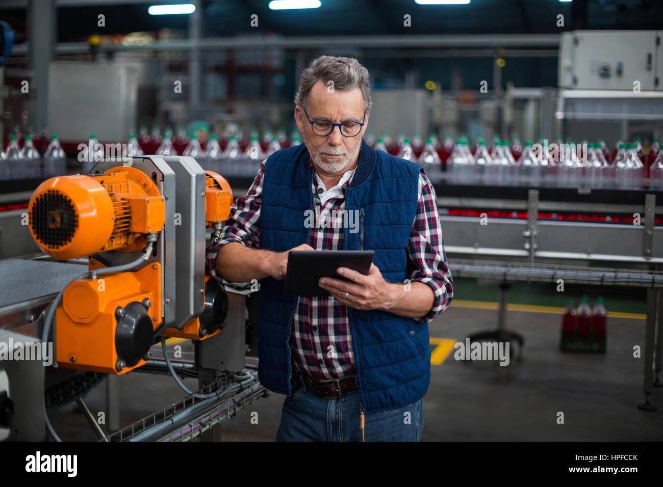 Factory worker using digital tablet next to production line in drinks ...