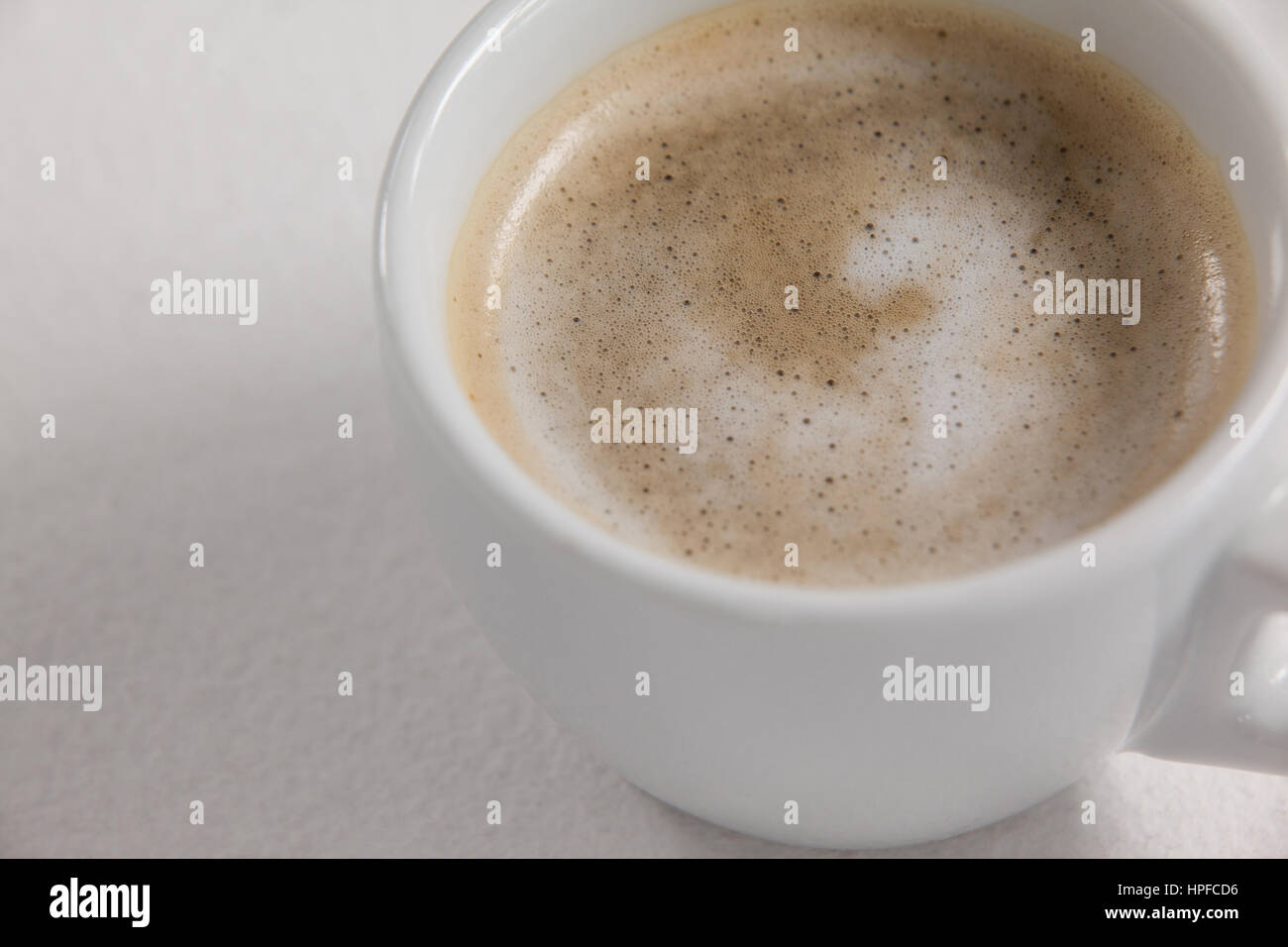 Close-up of white coffee cup with creamy froth on white background ...