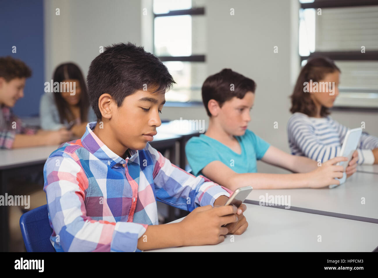 Students with digital tablet and mobile phone in classroom at school ...