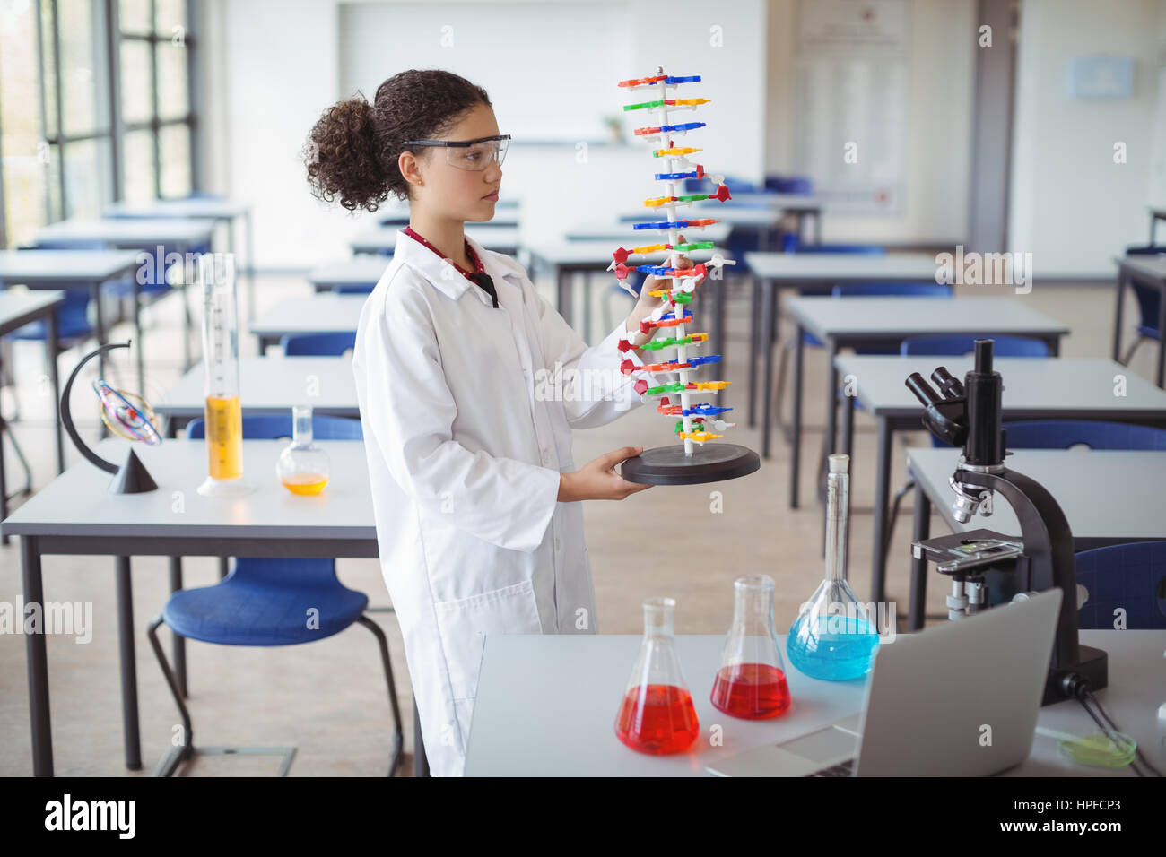 Attentive schoolgirl experimenting molecule model in laboratory at ...