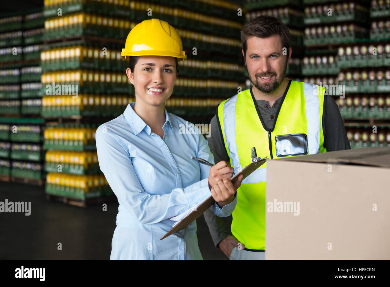 Portrait of factory workers maintaining record on clipboard in factory ...