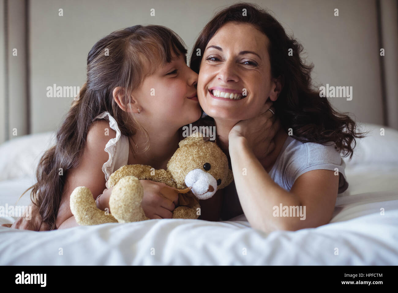Mother kissing daughter in bed hi-res stock photography and images - Alamy