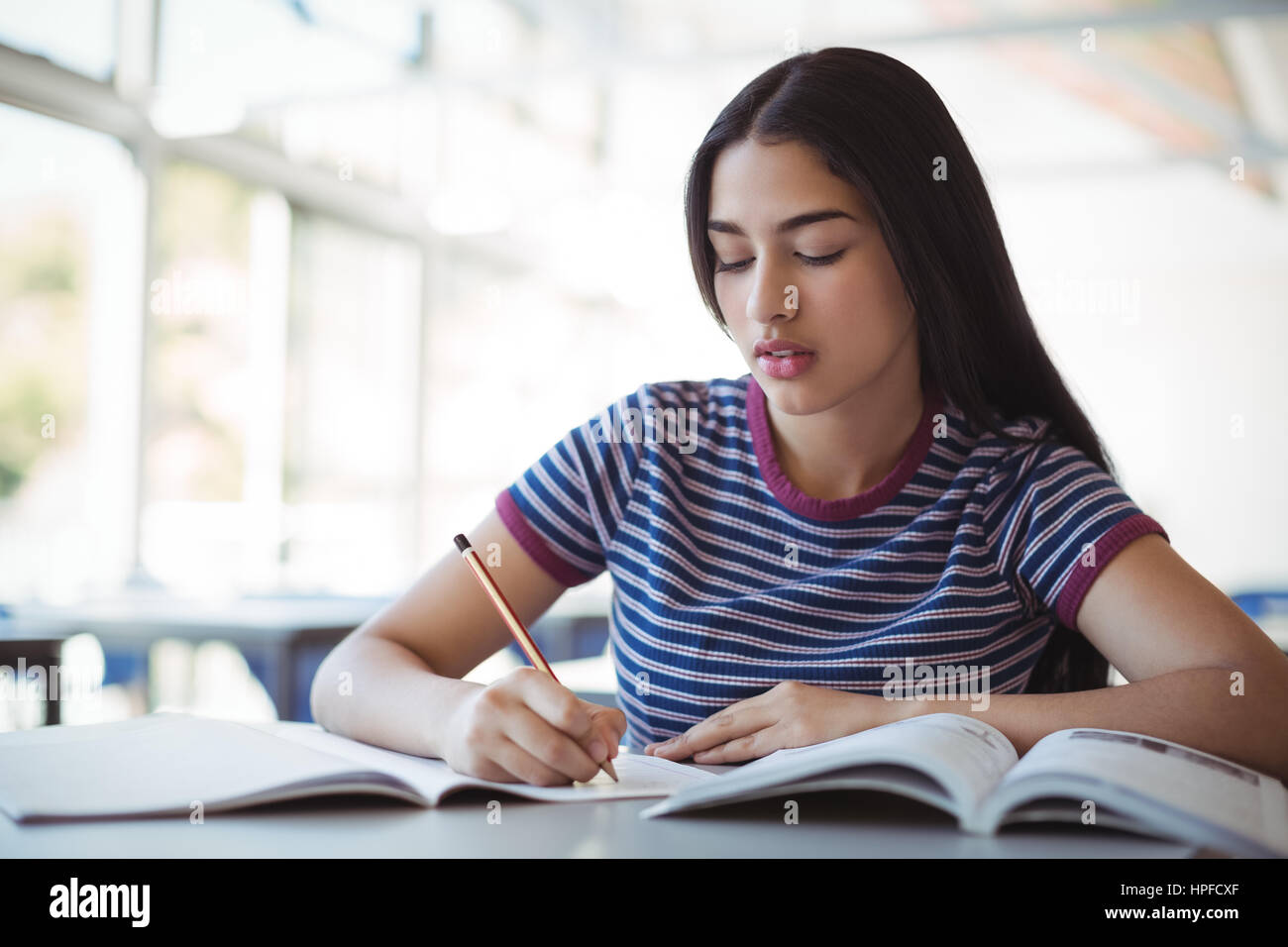 Attentive schoolgirl doing homework in classroom at school Stock Photo ...