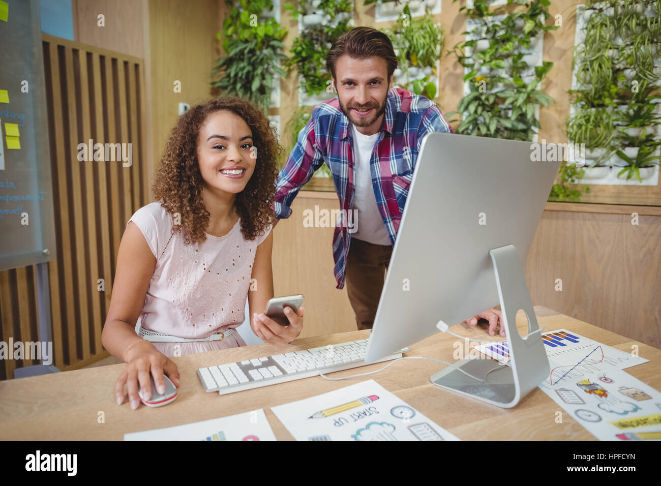 Portrait of executives smiling at desk while working on personal ...