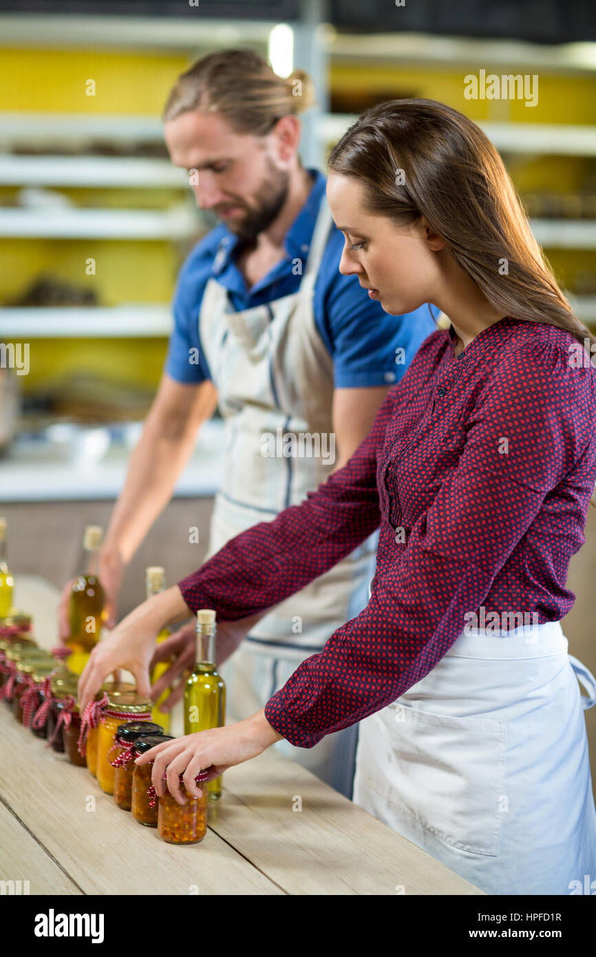 Shop assistants arranging jam and pickle jars at grocery shop Stock ...