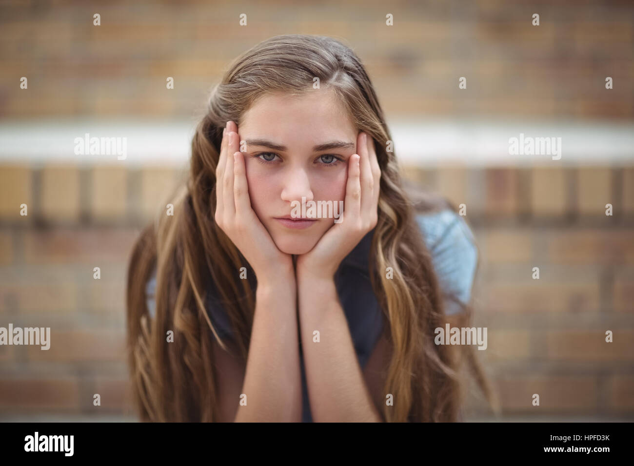 Portrait of sad schoolgirl sitting alone in campus at school Stock ...