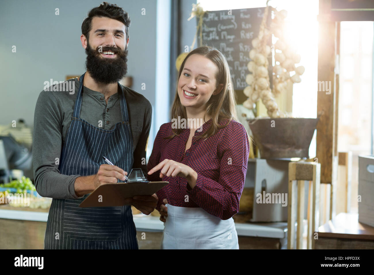 Portrait of smiling bakery staff writing on clipboard at counter in ...
