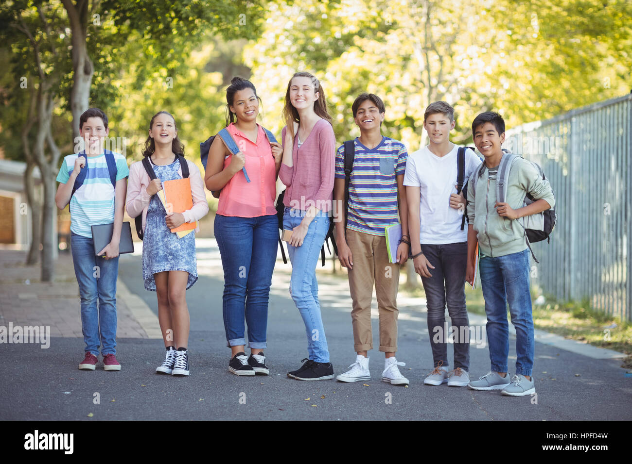 Portrait of happy students standing with books on road at school Stock ...