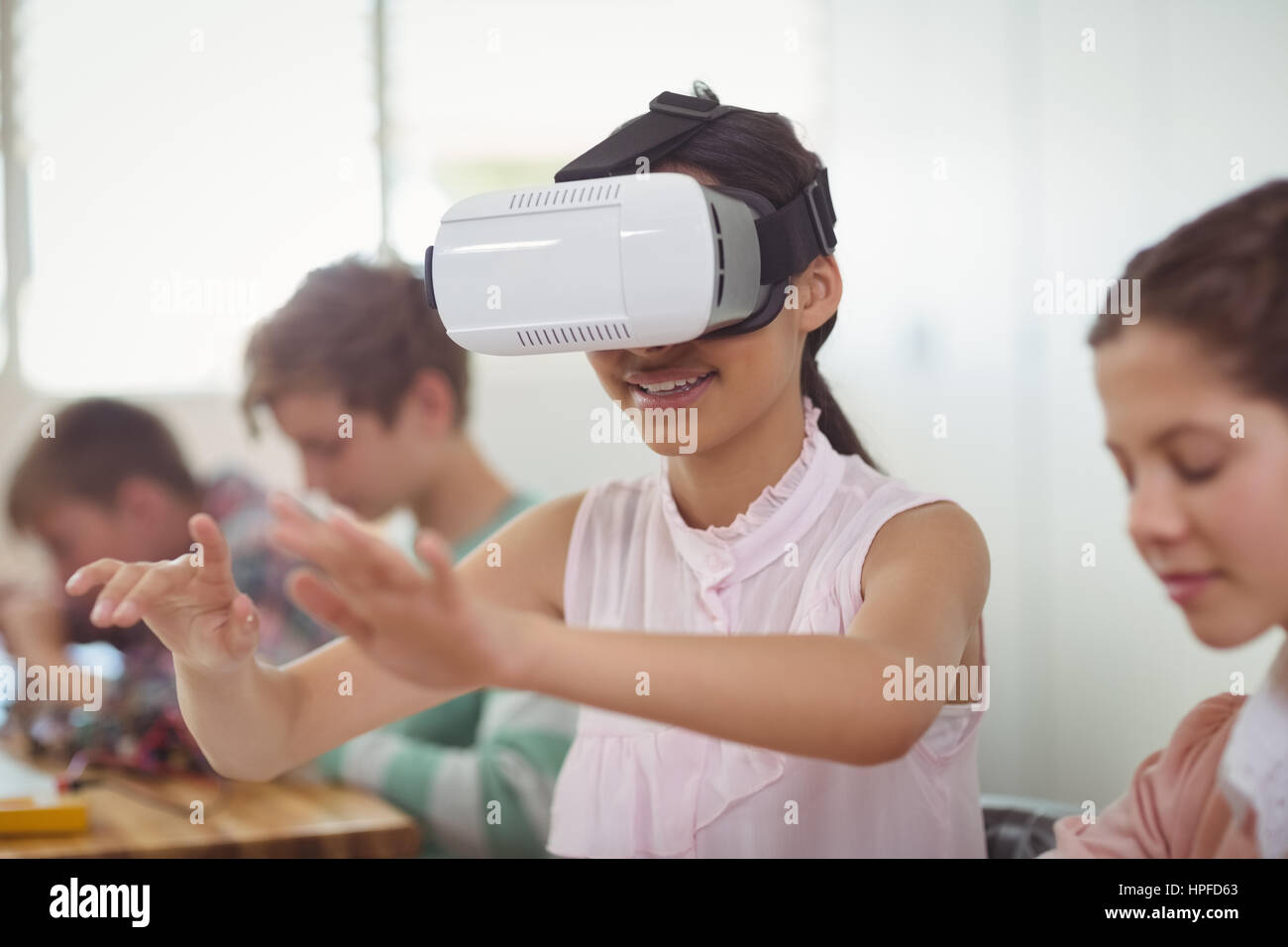 School girl sitting in classroom using virtual reality headset at ...