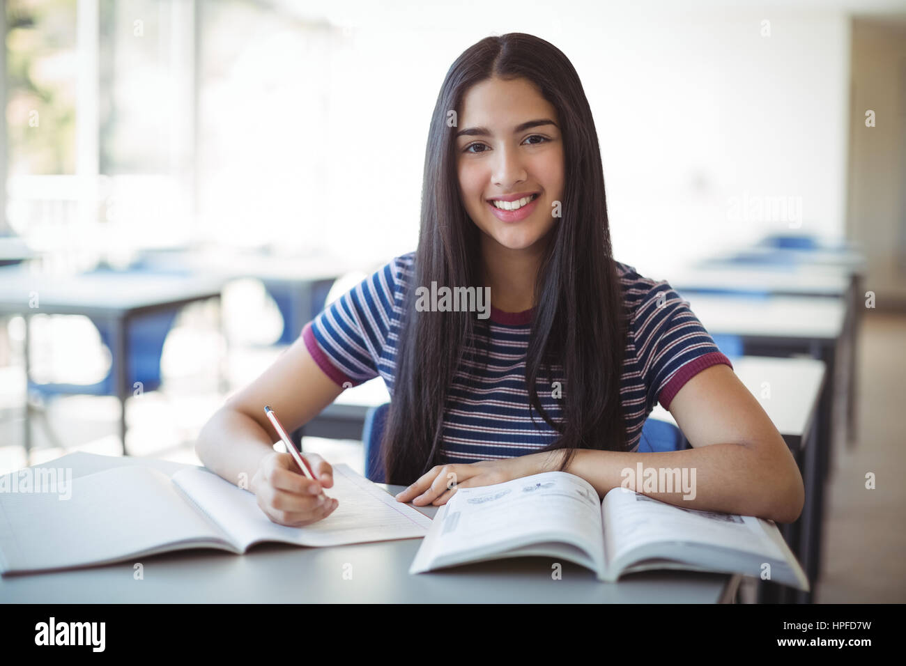 Schoolgirl doing homework in classroom at school Stock Photo - Alamy