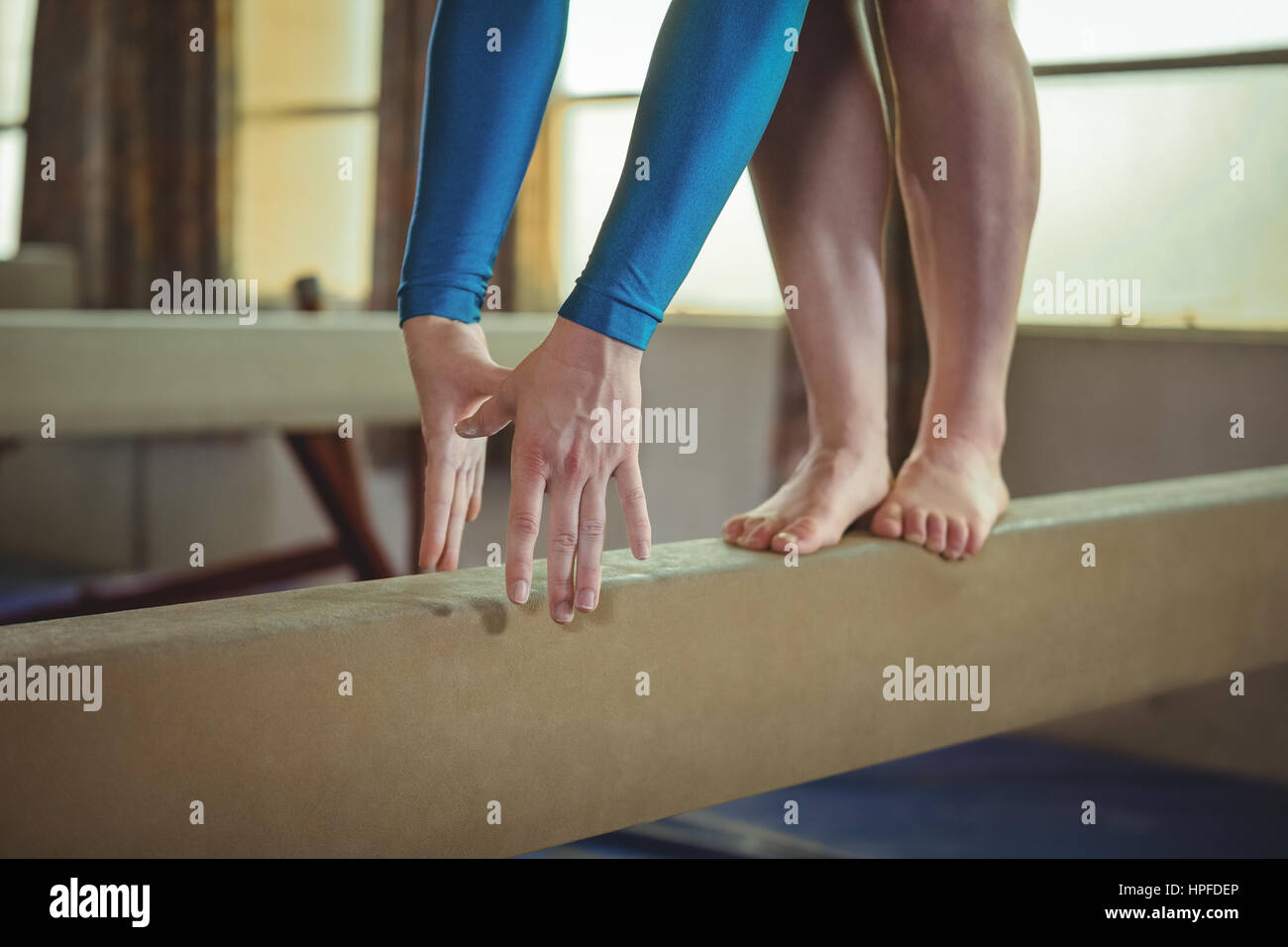 Low-section of female gymnast practicing gymnastics on the balance beam ...