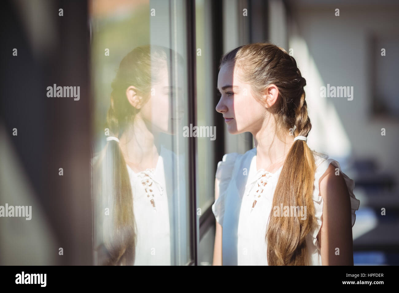 Schoolgirl looking through window in classroom at school Stock Photo ...